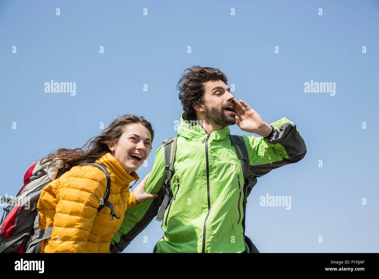 Hiking couple against blue sky laughing and shouting Stock Photo - Alamy