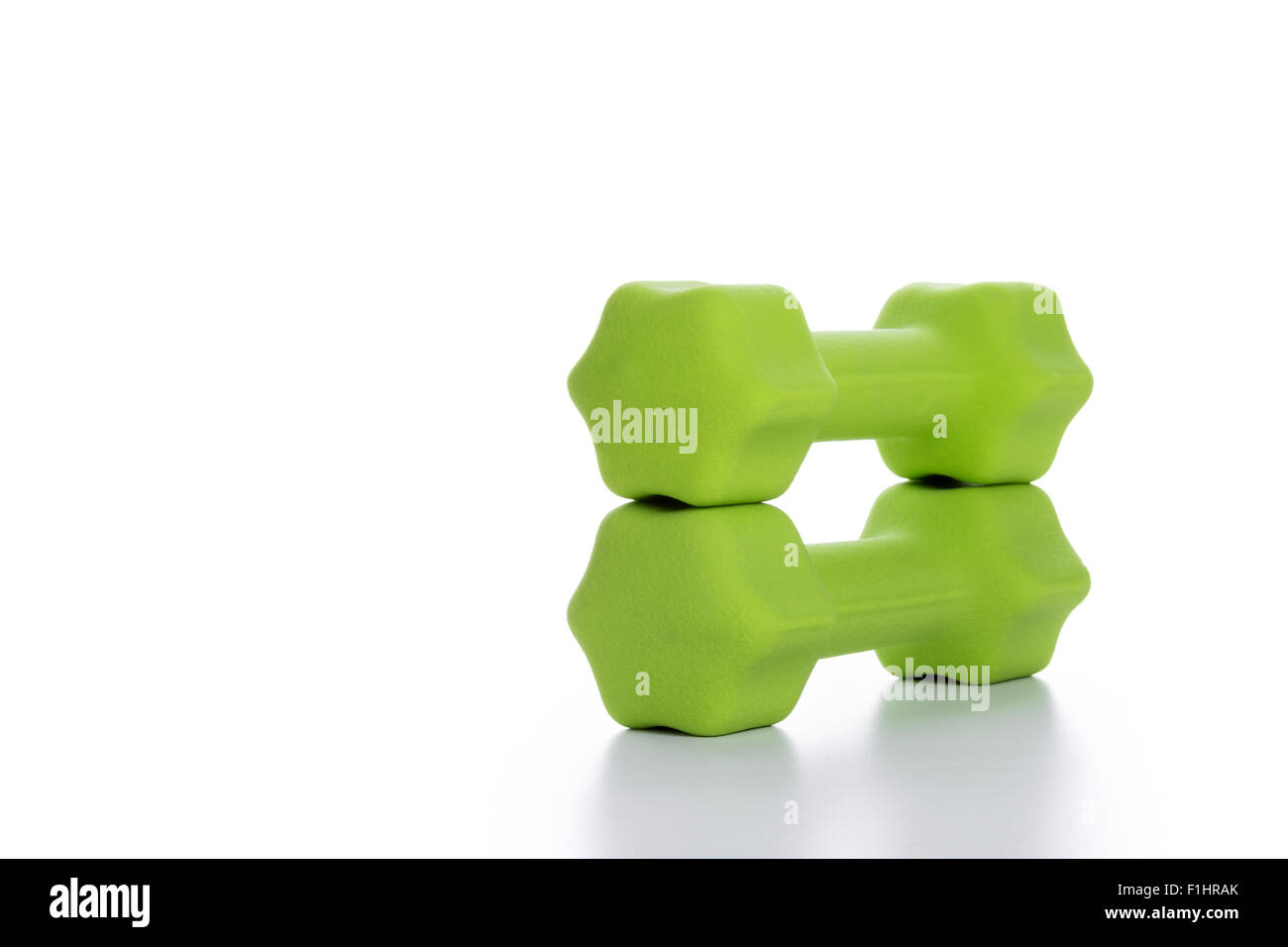Fitness concept with two green dumbbells on white background, closeup ...