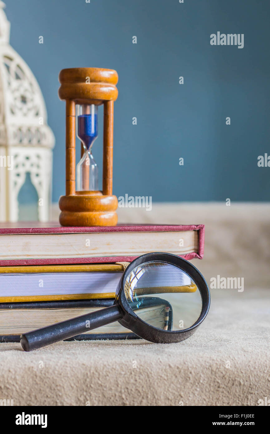 Magnifying glass and hourglass on a book Stock Photo - Alamy