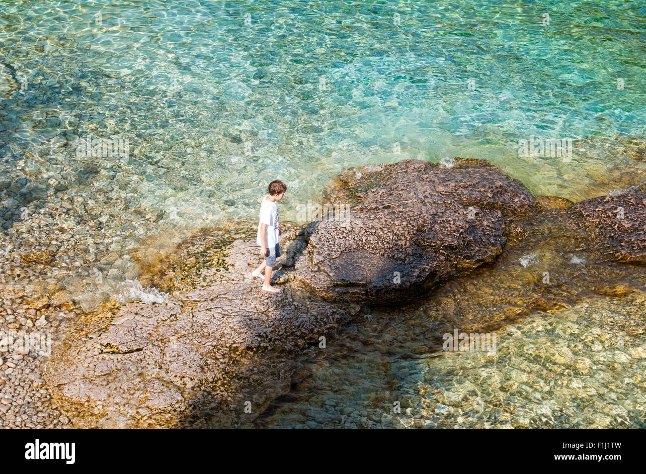 child standing on rocks looking into the clear clean waters of Bruce ...
