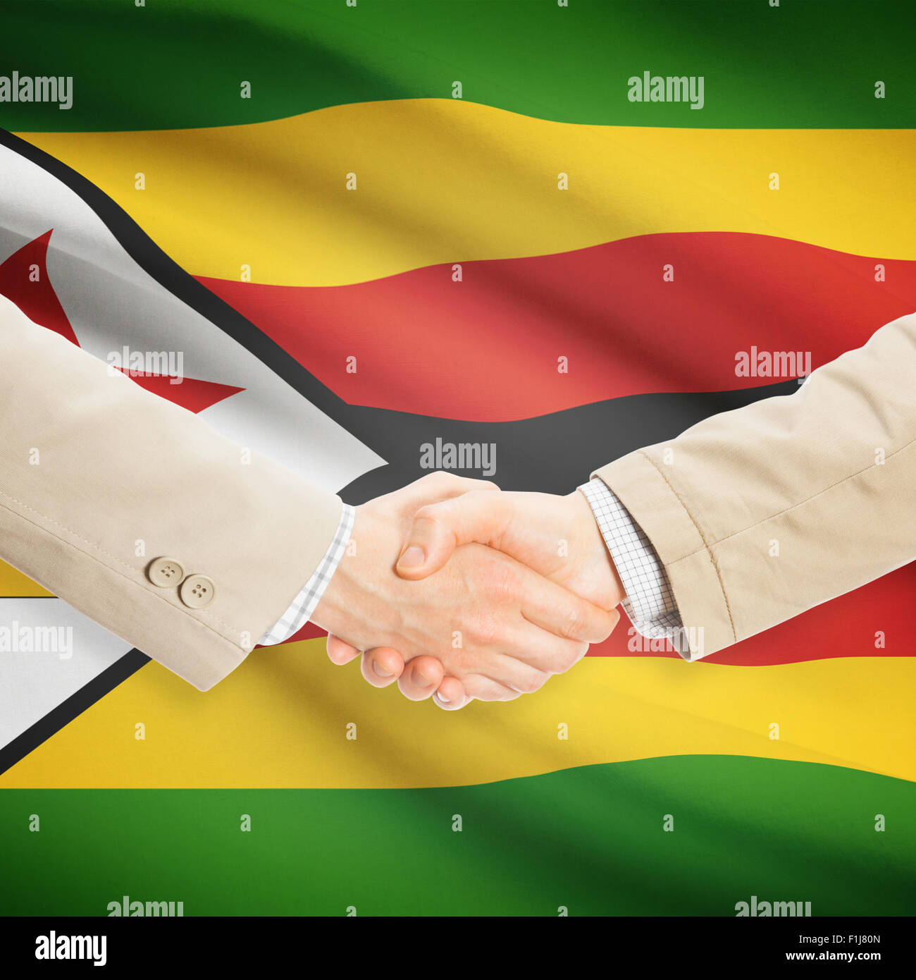 Businessmen shaking hands with flag on background - Zimbabwe Stock ...
