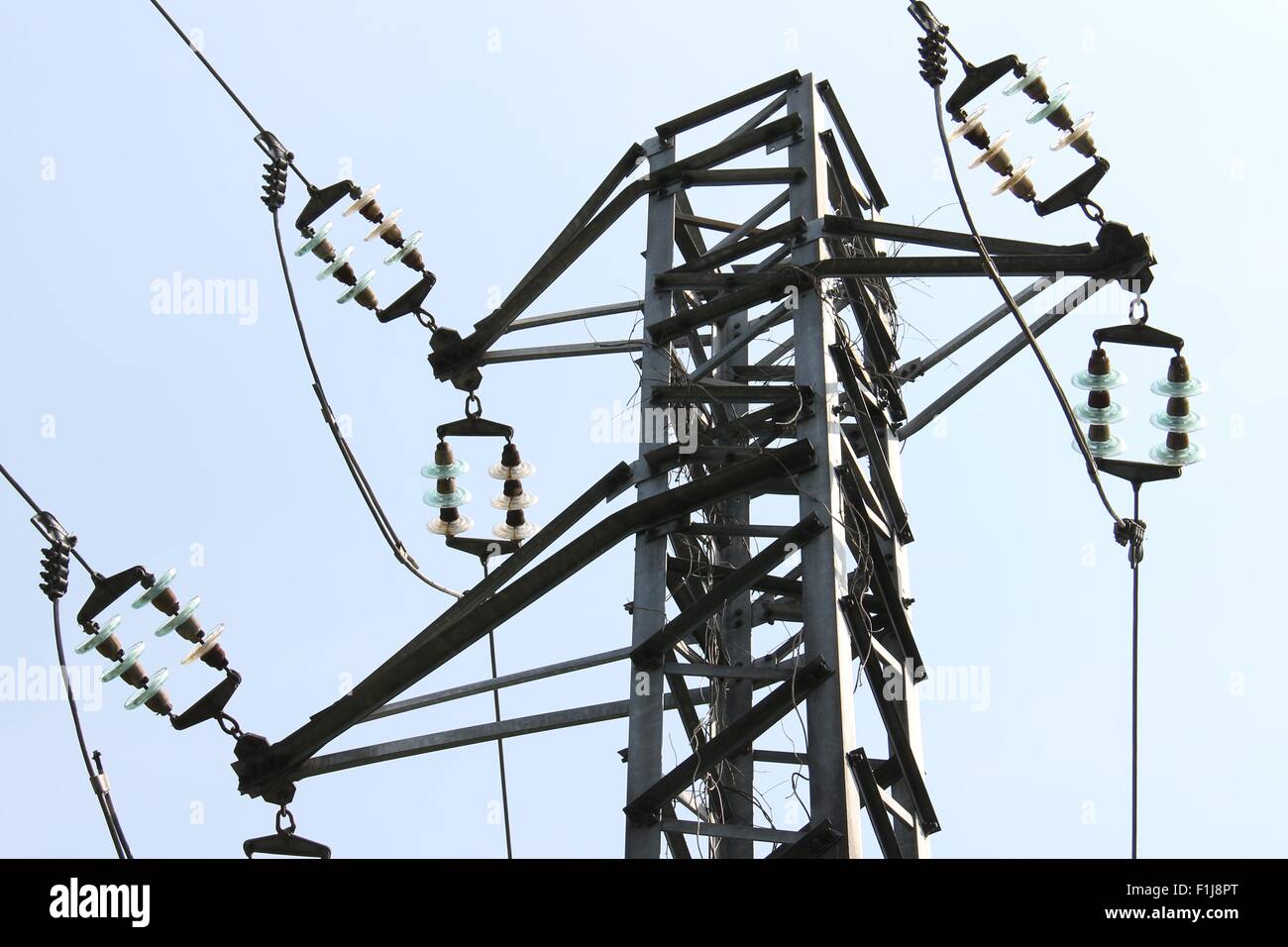 Transformers of an electrical post with power lines against bright sky ...