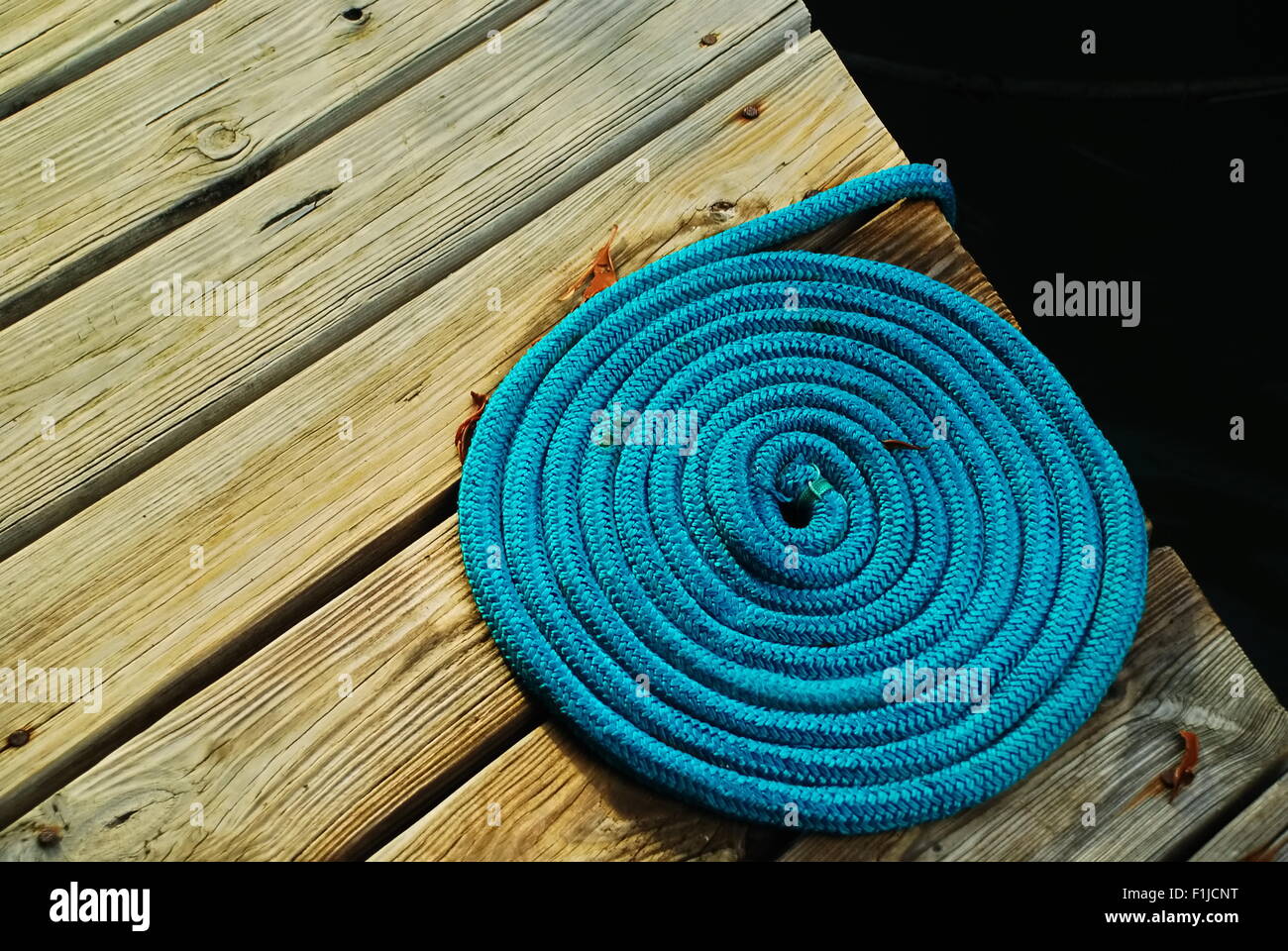 Coiled turquoise blue rope on wooden dock Stock Photo - Alamy