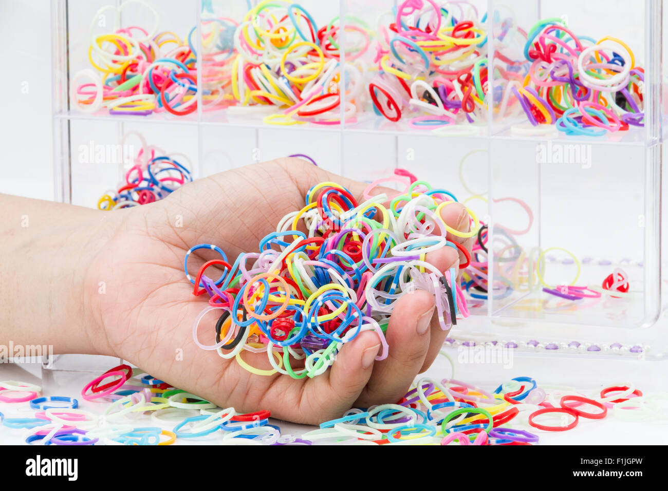 hands and pile of small round colorful rubber bands rainbow color for ...