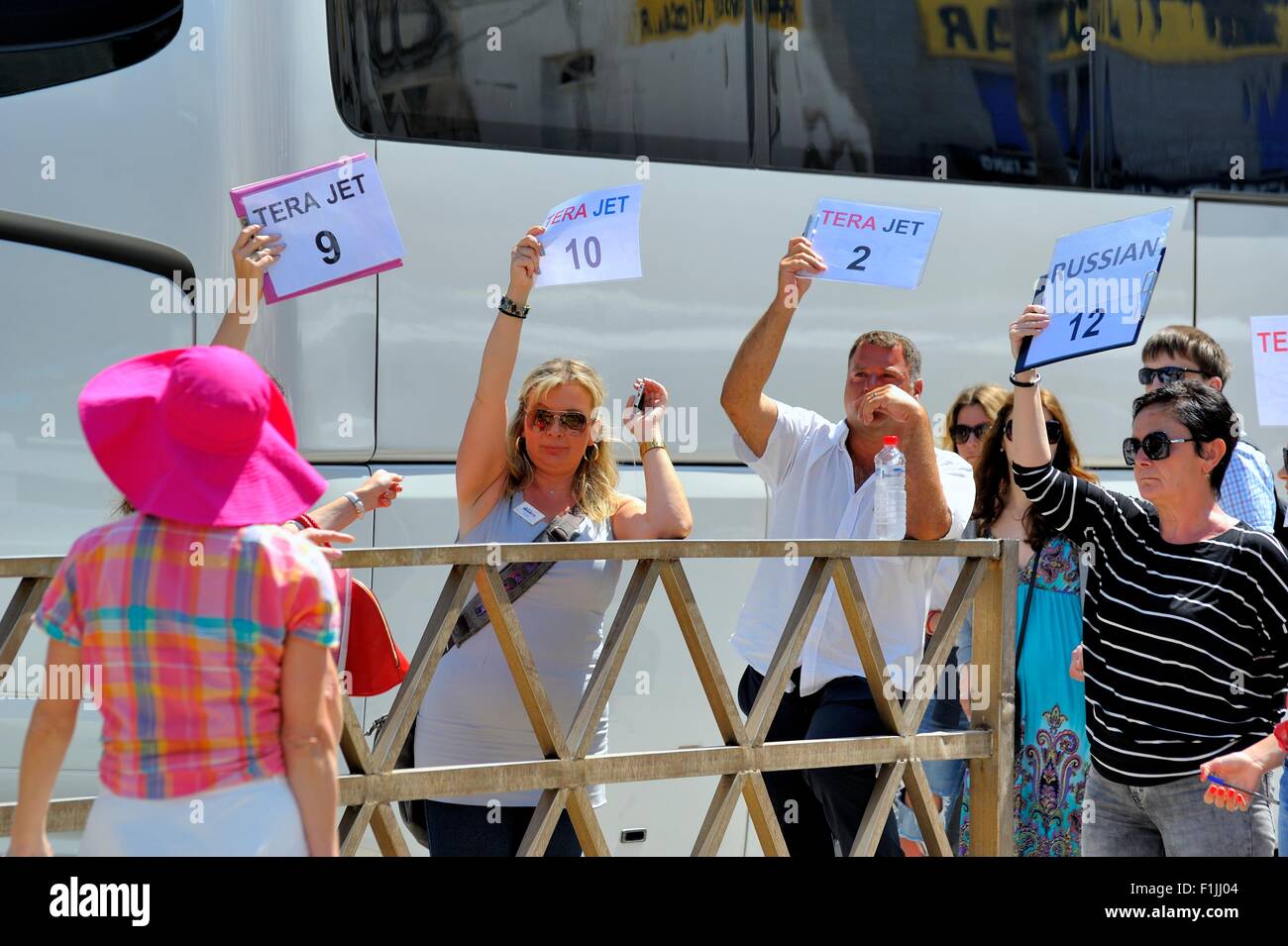 Day trip tour reps holding up tour trip numbers for passengers as they ...