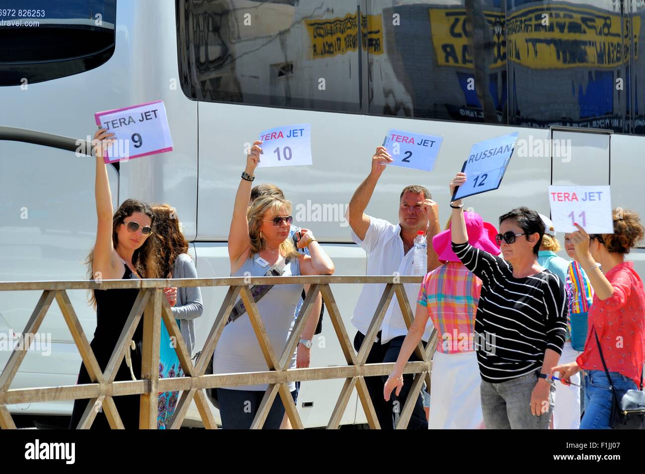 Day trip tour reps holding up tour trip numbers for passengers as they ...
