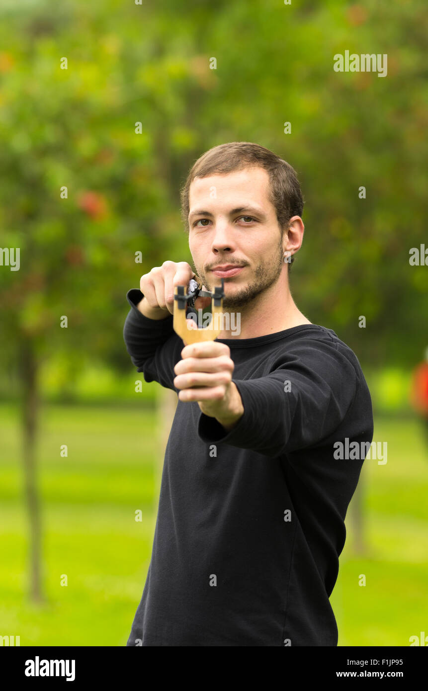 Handsome man concentrated aiming a slingshot at park having fun Stock ...