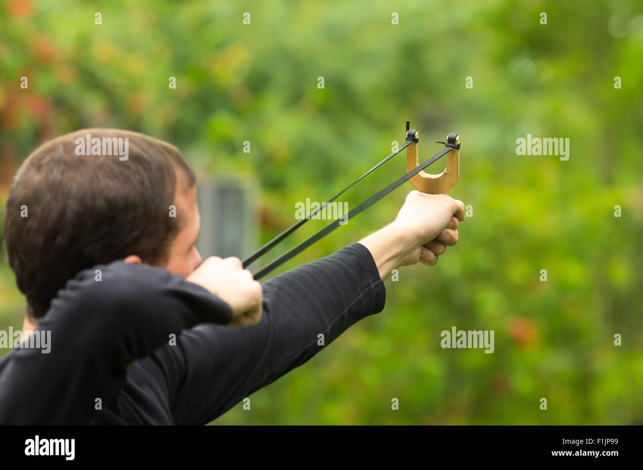 Handsome man concentrated aiming a slingshot at park having fun Stock ...