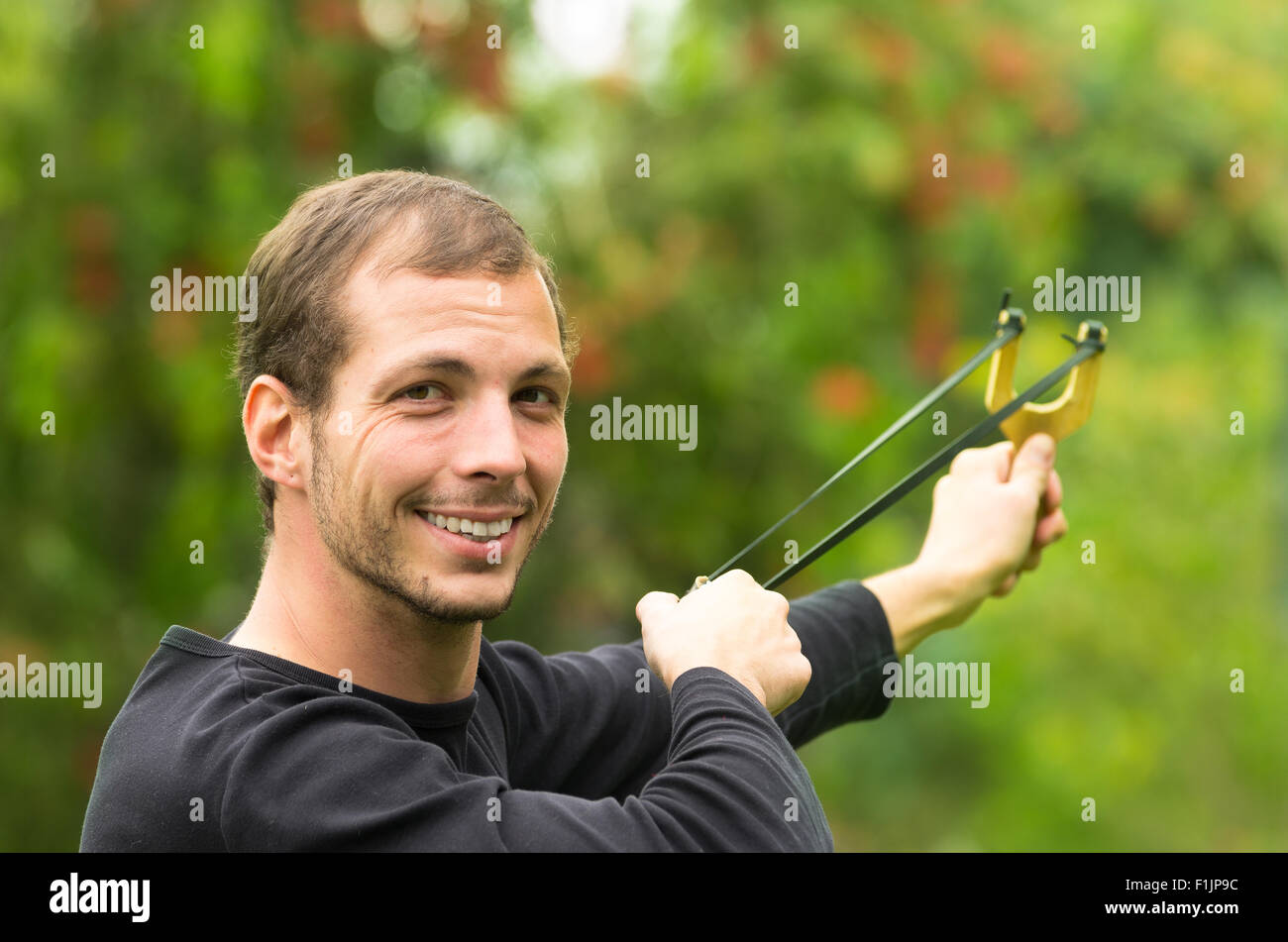 Handsome man concentrated aiming a slingshot at park having fun Stock ...