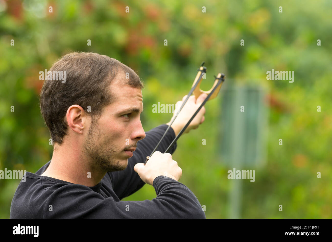 Handsome man concentrated aiming a slingshot at park having fun Stock ...