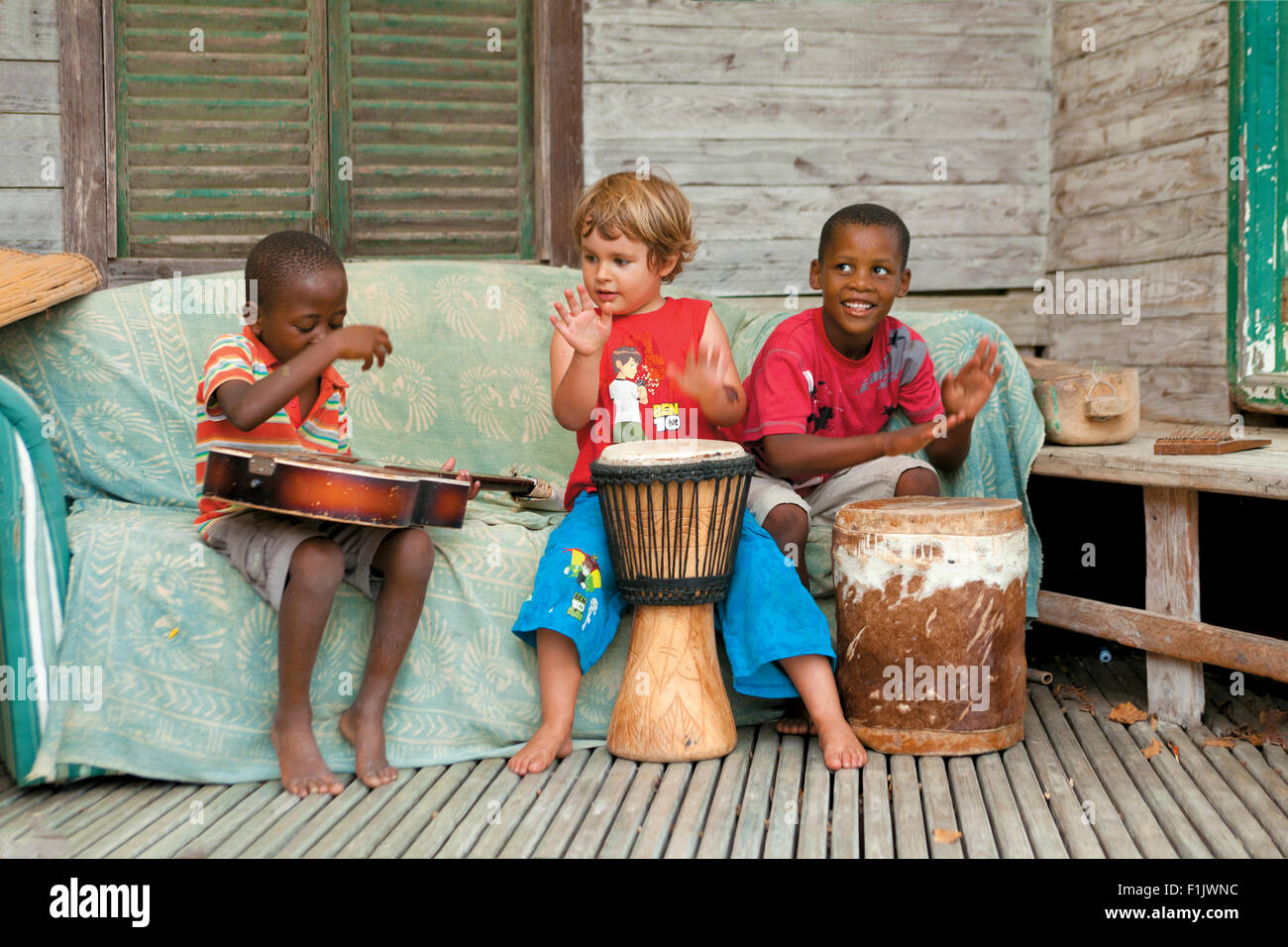 Children sitting on a couch playing musical instruments together Stock ...