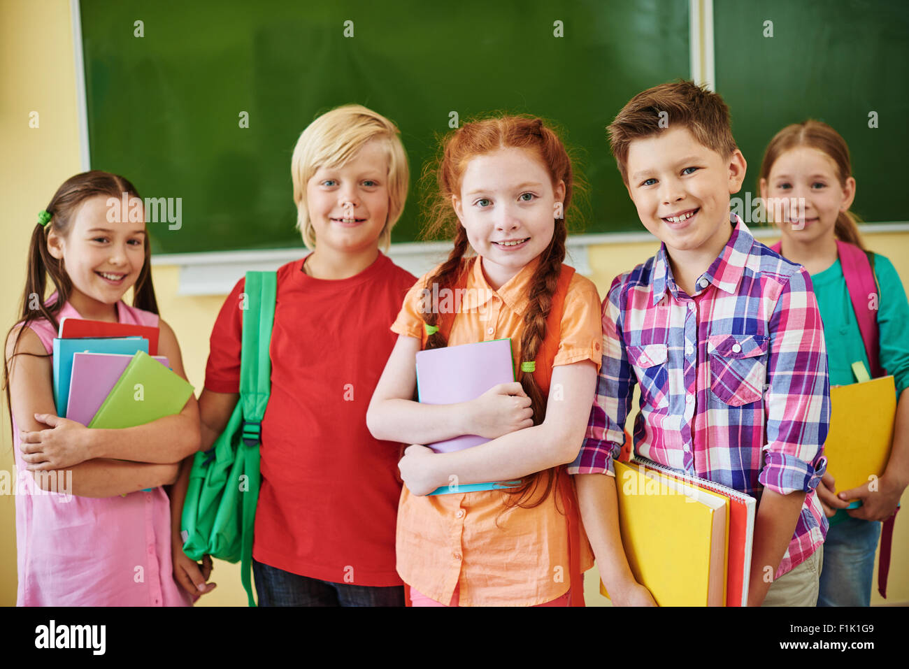 Happy schoolkids with books looking at camera Stock Photo - Alamy