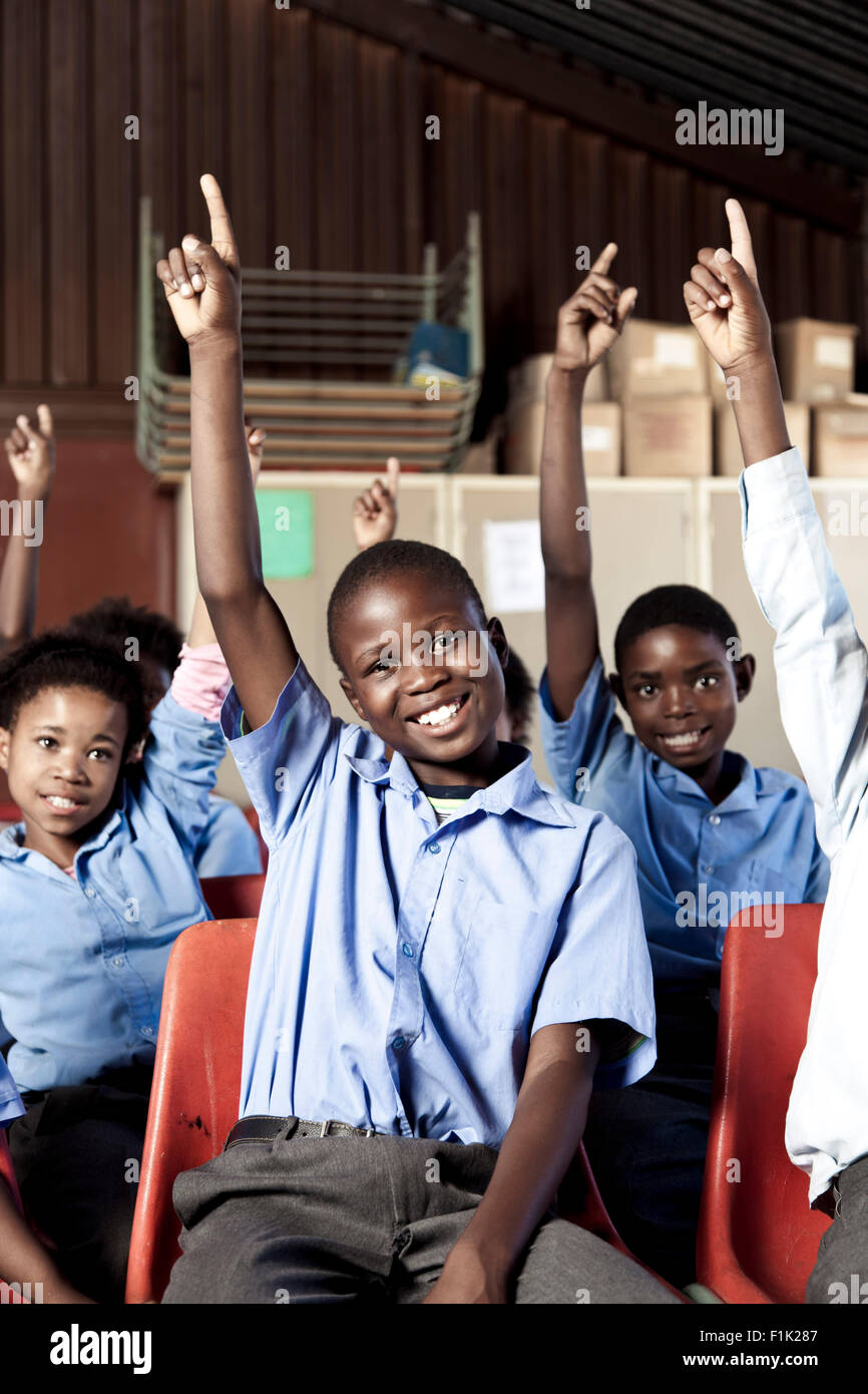 African school pupils smiling at camera with their hands in the air ...