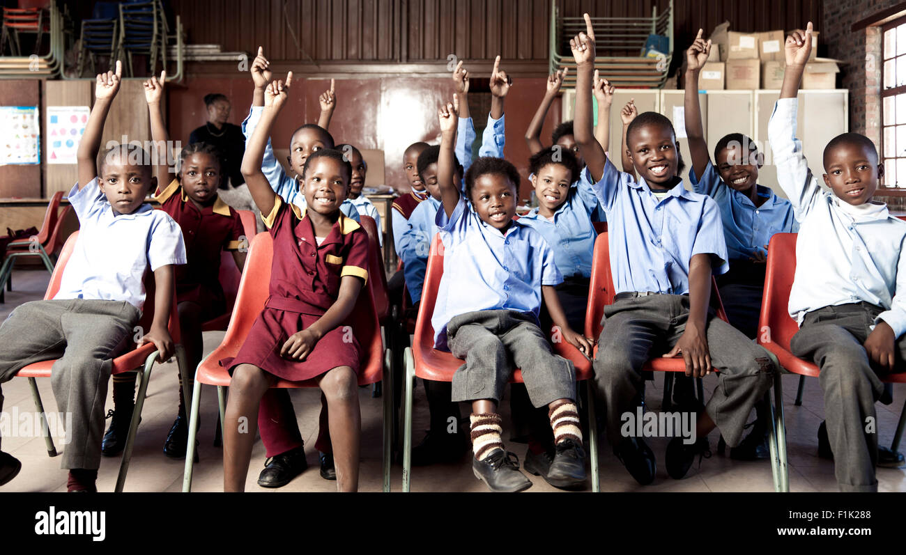 African school pupils smiling at camera with their hands in the air ...