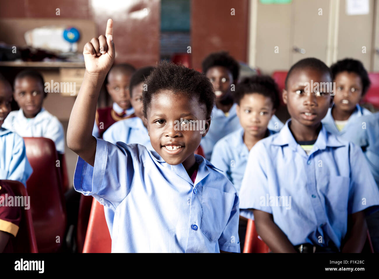African school pupils smiling at camera with their hands in the air ...