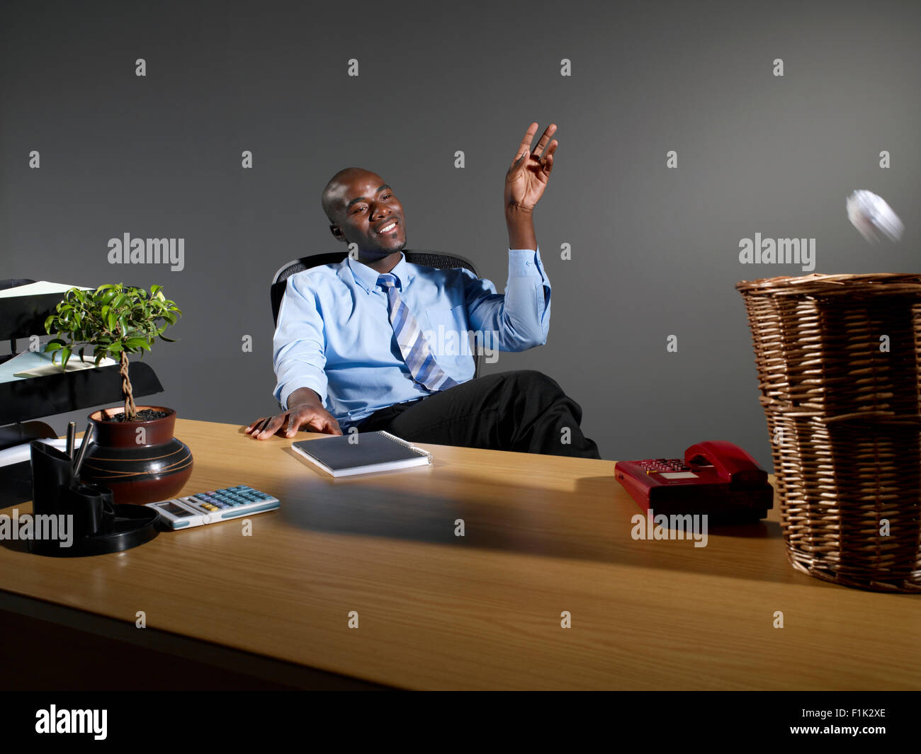 Bored businessman tossing paper balls into waste basket Stock Photo - Alamy
