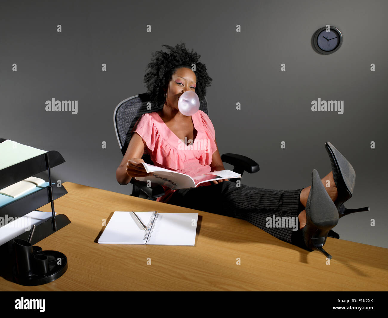 Bored woman blowing bubbles while sitting at her desk Stock Photo - Alamy