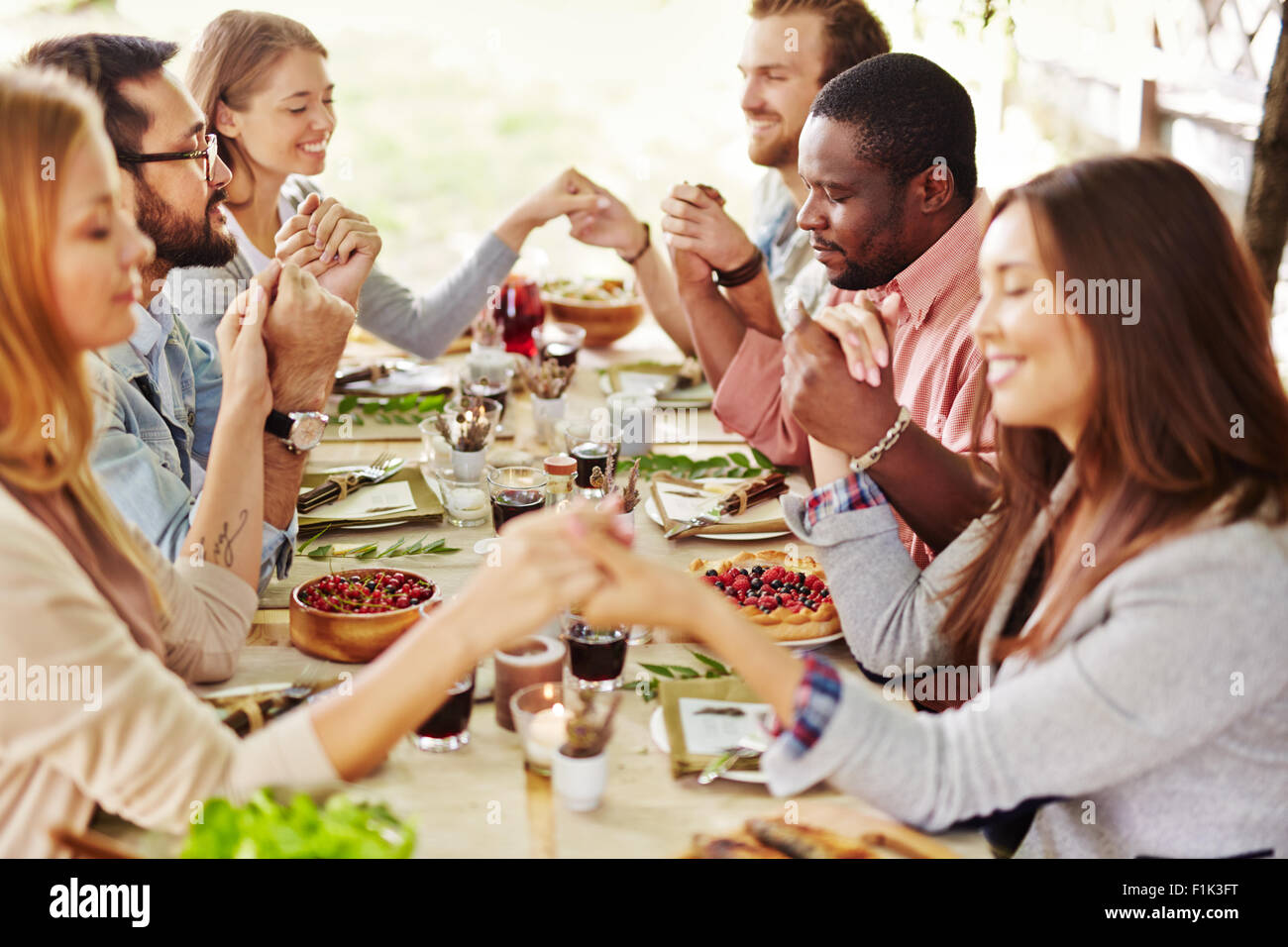 Group of young friends praying at Thanksgiving table Stock Photo - Alamy