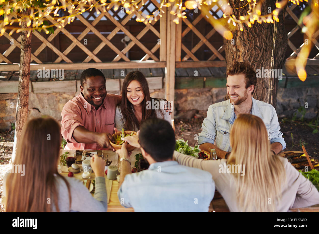 Happy young couple offering their friends traditional food by ...
