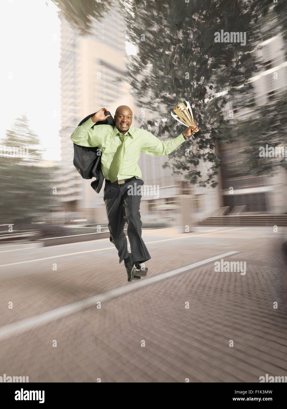 Business man running with trophy Stock Photo - Alamy