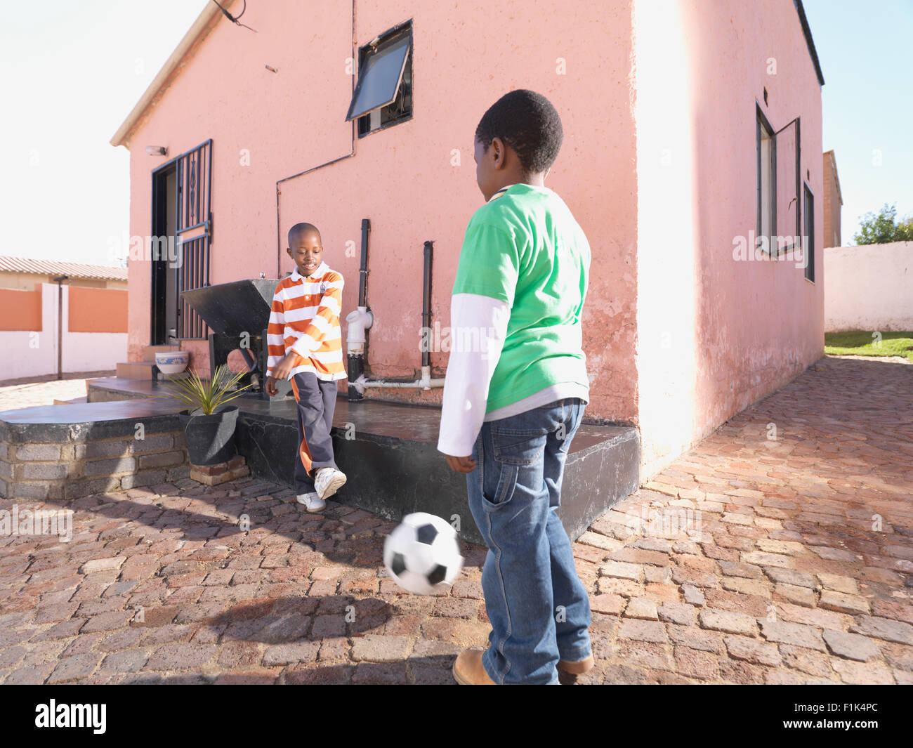 Boys playing soccer outside house Stock Photo - Alamy