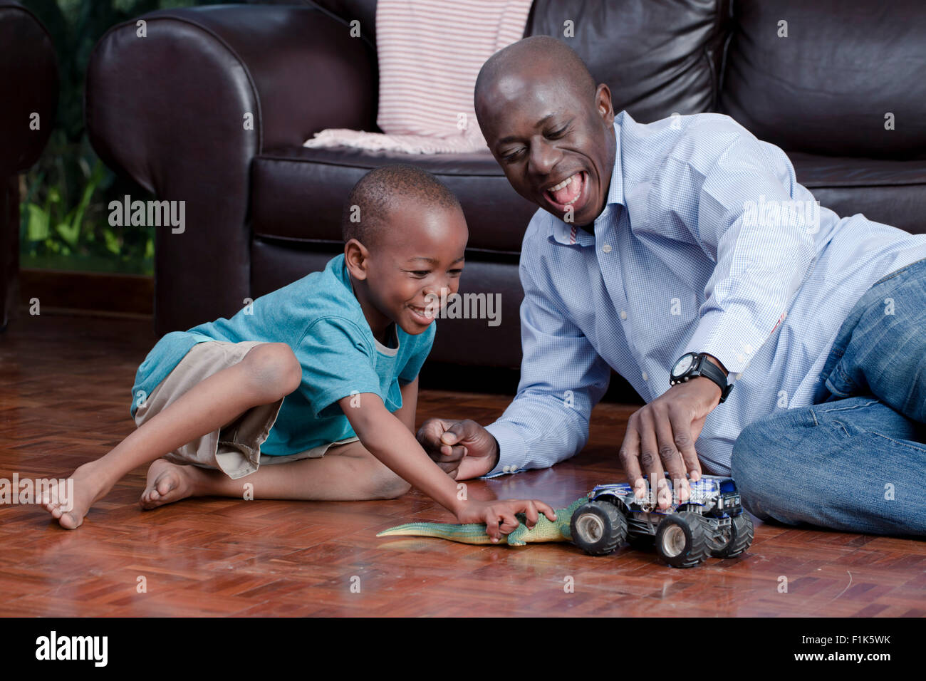 Young African father playing with his son on the floor of the living ...