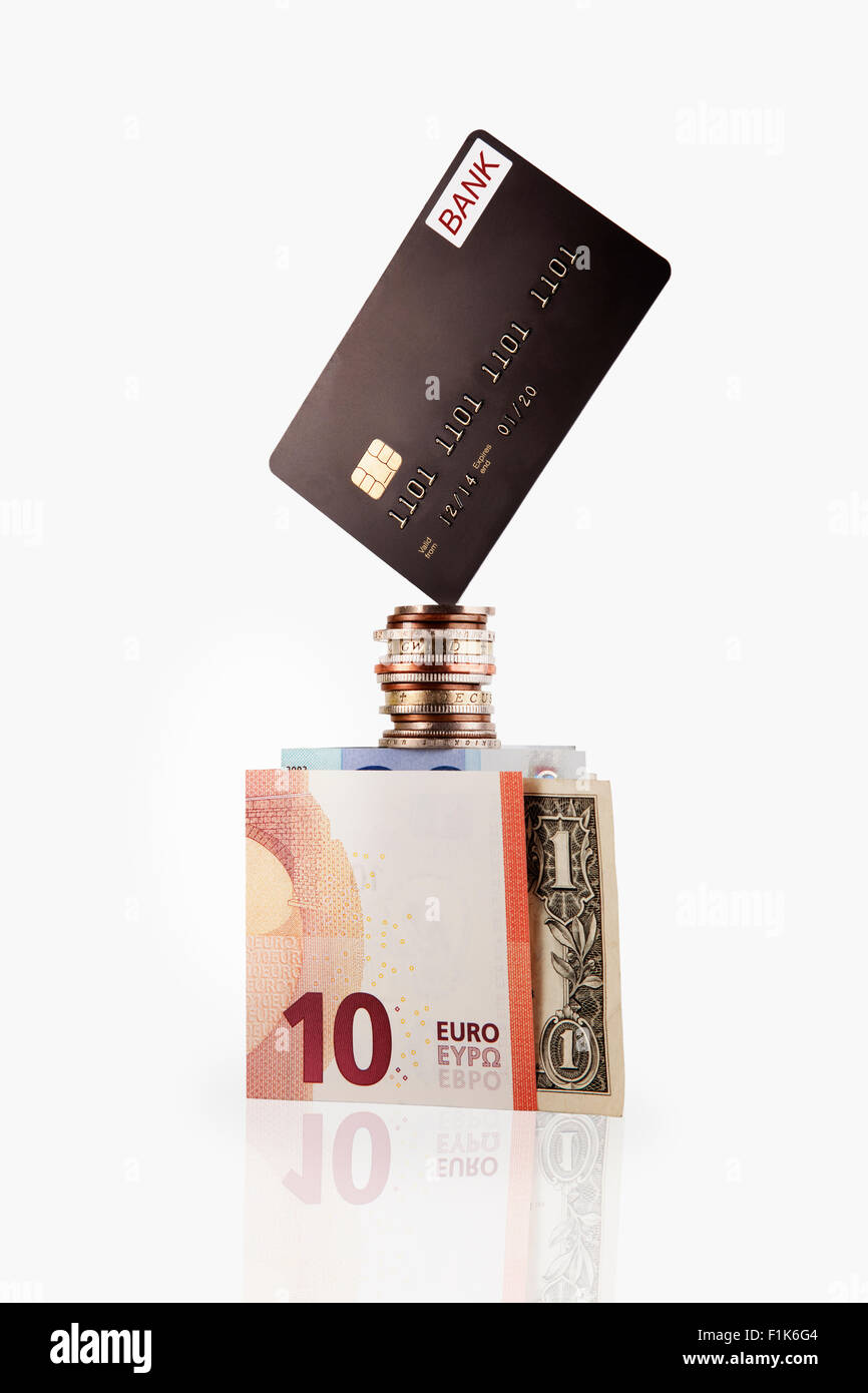 Credit card balancing on coins and cash Stock Photo - Alamy