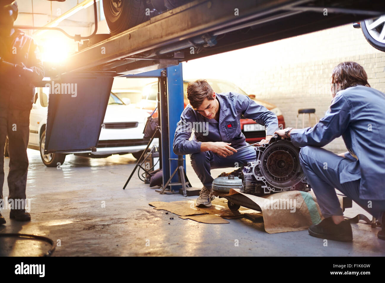 Mechanics examining part in auto repair shop Stock Photo - Alamy