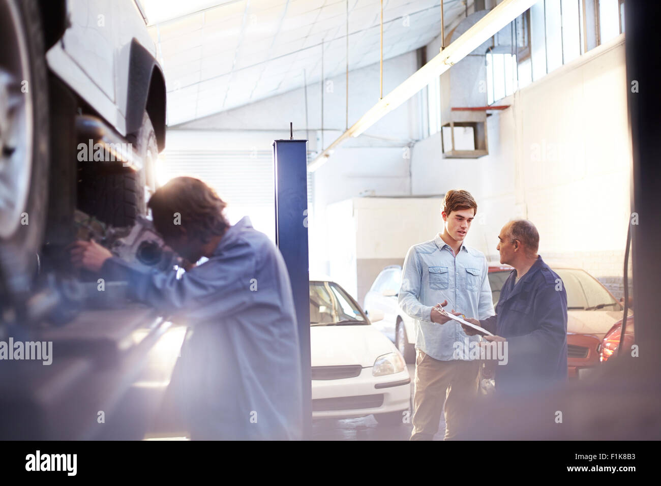 Mechanic speaking with customer in auto repair shop Stock Photo - Alamy