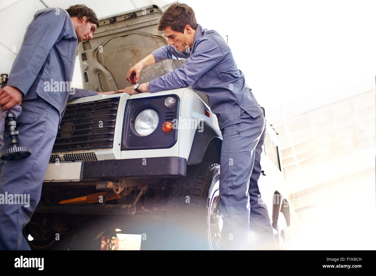 Mechanics working on engine in auto repair shop Stock Photo - Alamy