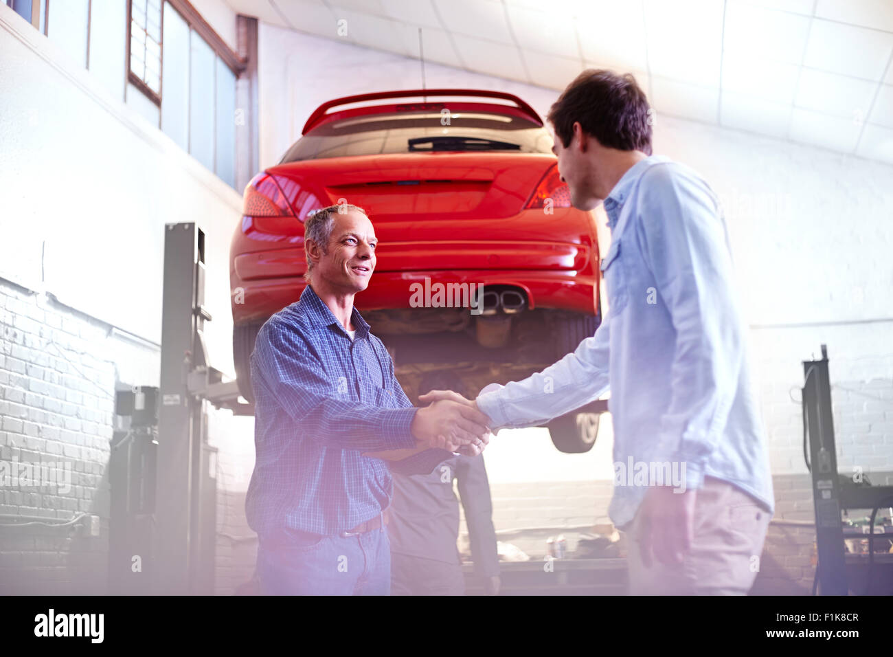 Mechanic and customer handshaking in auto repair shop Stock Photo - Alamy
