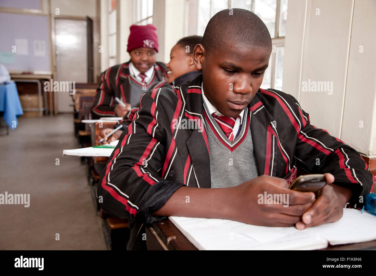 A male student playing with his cellphone in class Stock Photo - Alamy