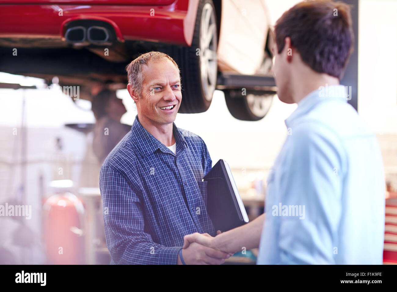 Mechanic and customer handshaking in auto repair shop Stock Photo - Alamy