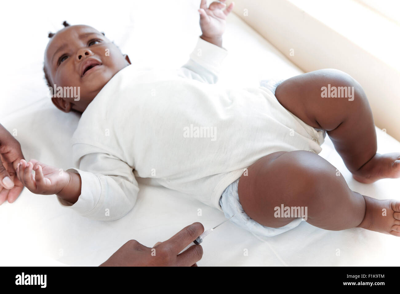 African infant lying on a ward bed being examined by doctor Stock Photo ...