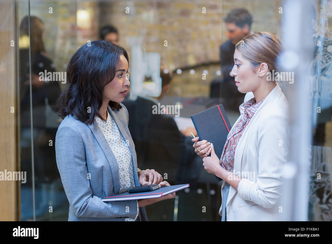 Businesswomen talking outside conference room meeting Stock Photo - Alamy