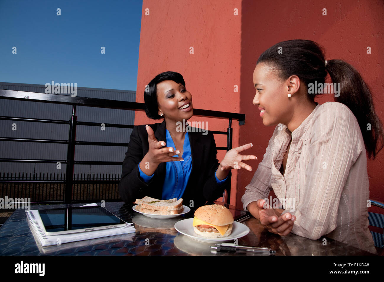 Two female colleagues talk over lunch, smiling Stock Photo - Alamy