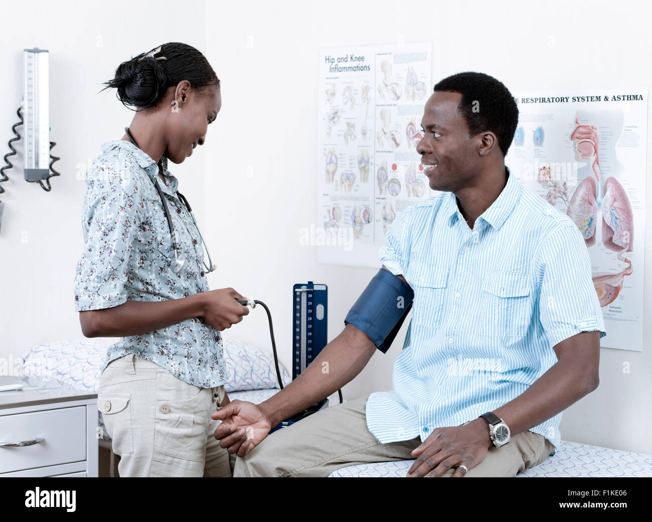 Female African doctor checking young African man's blood pressure Stock ...