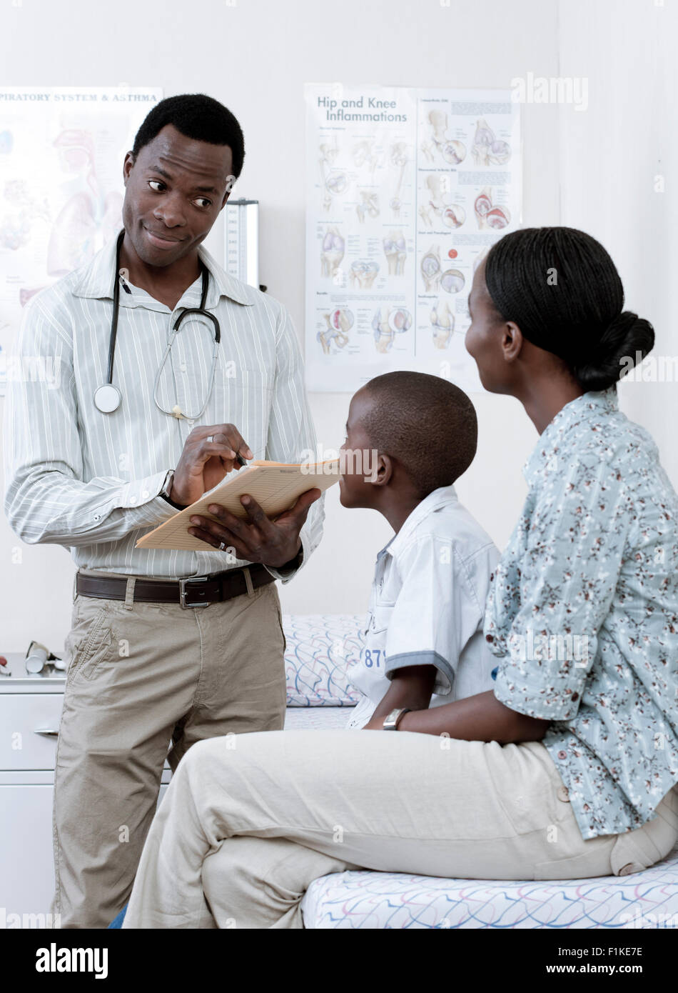 Doctor examining male African child in a doctor's room, with a young ...