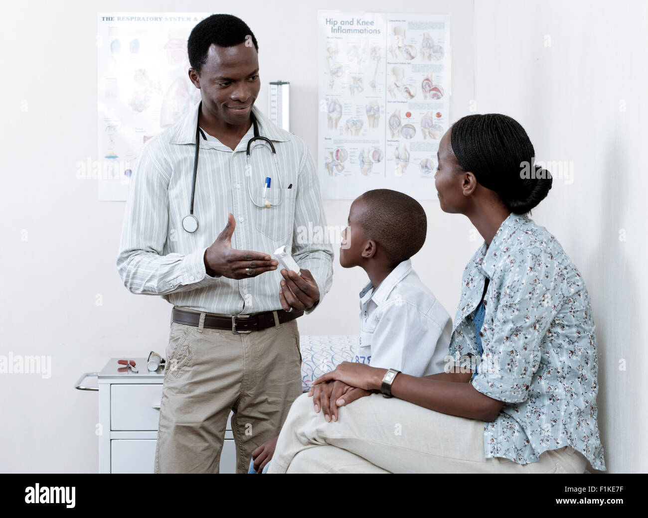 Doctor examining male African child in a doctor's room, with a young ...