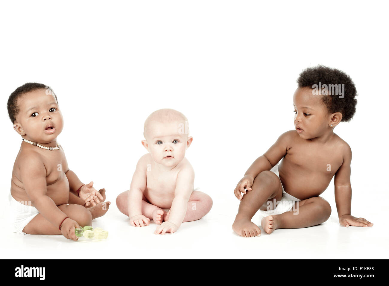 Three infants sitting in front of a white background Stock Photo - Alamy