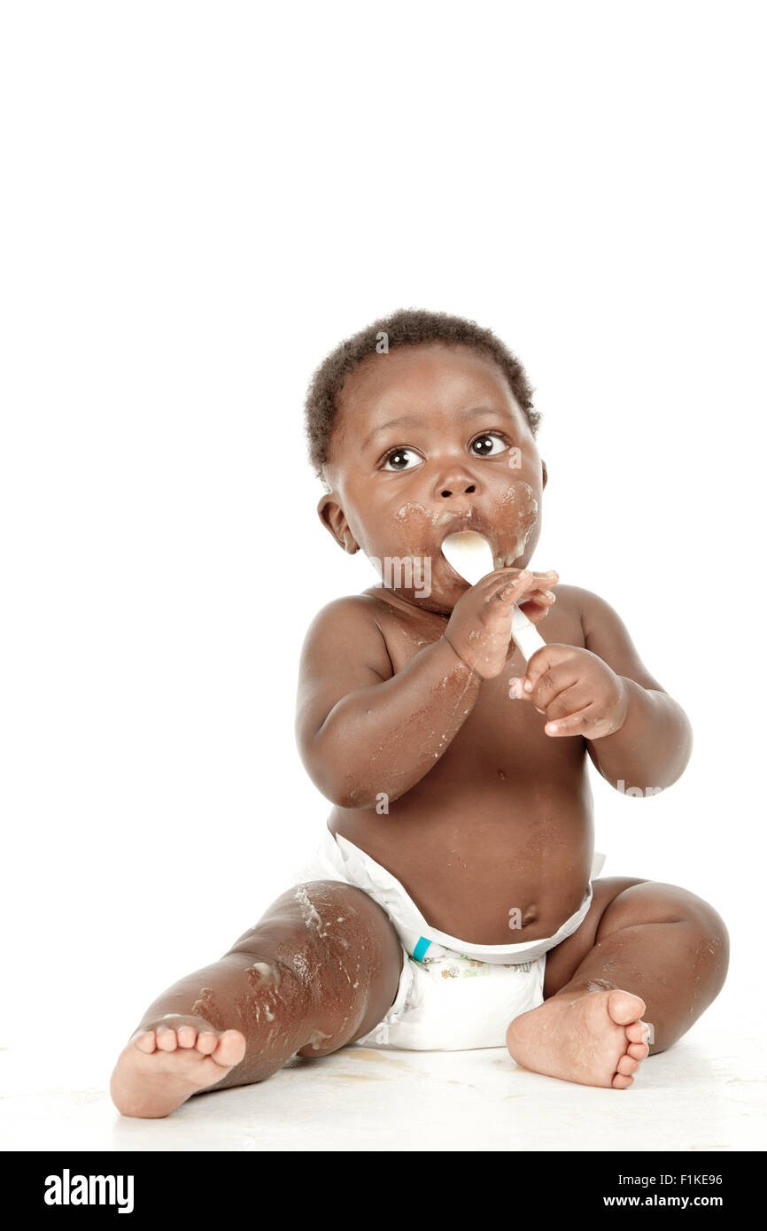 An infant sitting in front of a white background, eating Stock Photo ...