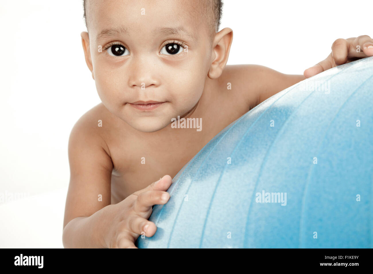 Infant sitting in front of a white background with an exercise ball ...