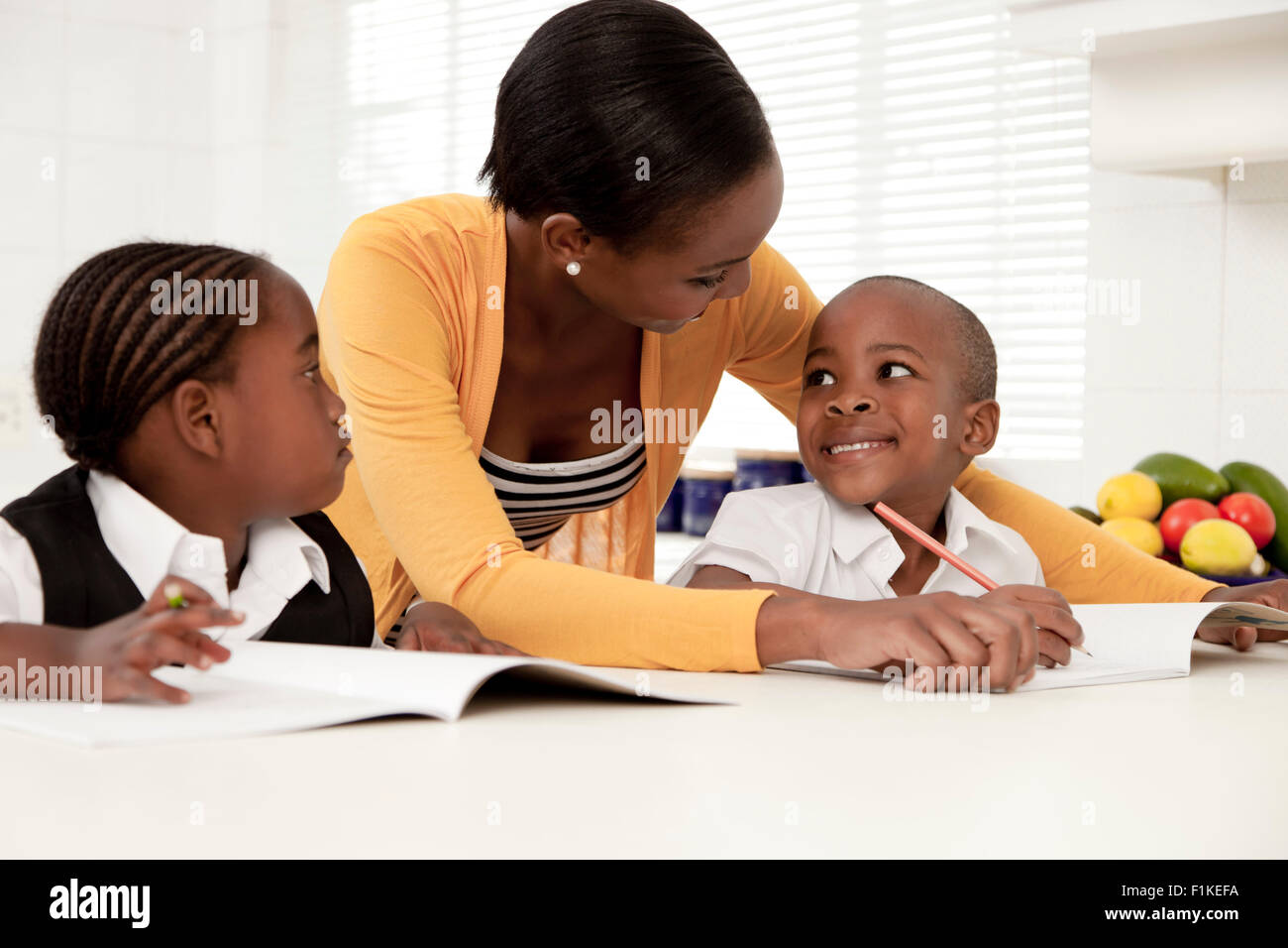 Young African mother helping her children with their homework Stock ...