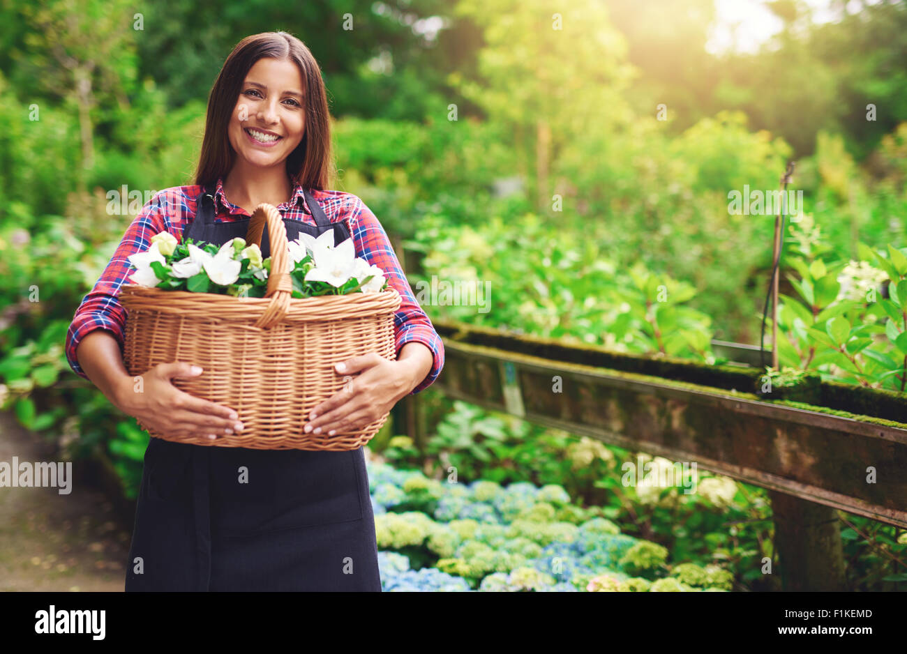 Young woman florist working outdoors at the nursery gathering flowers ...