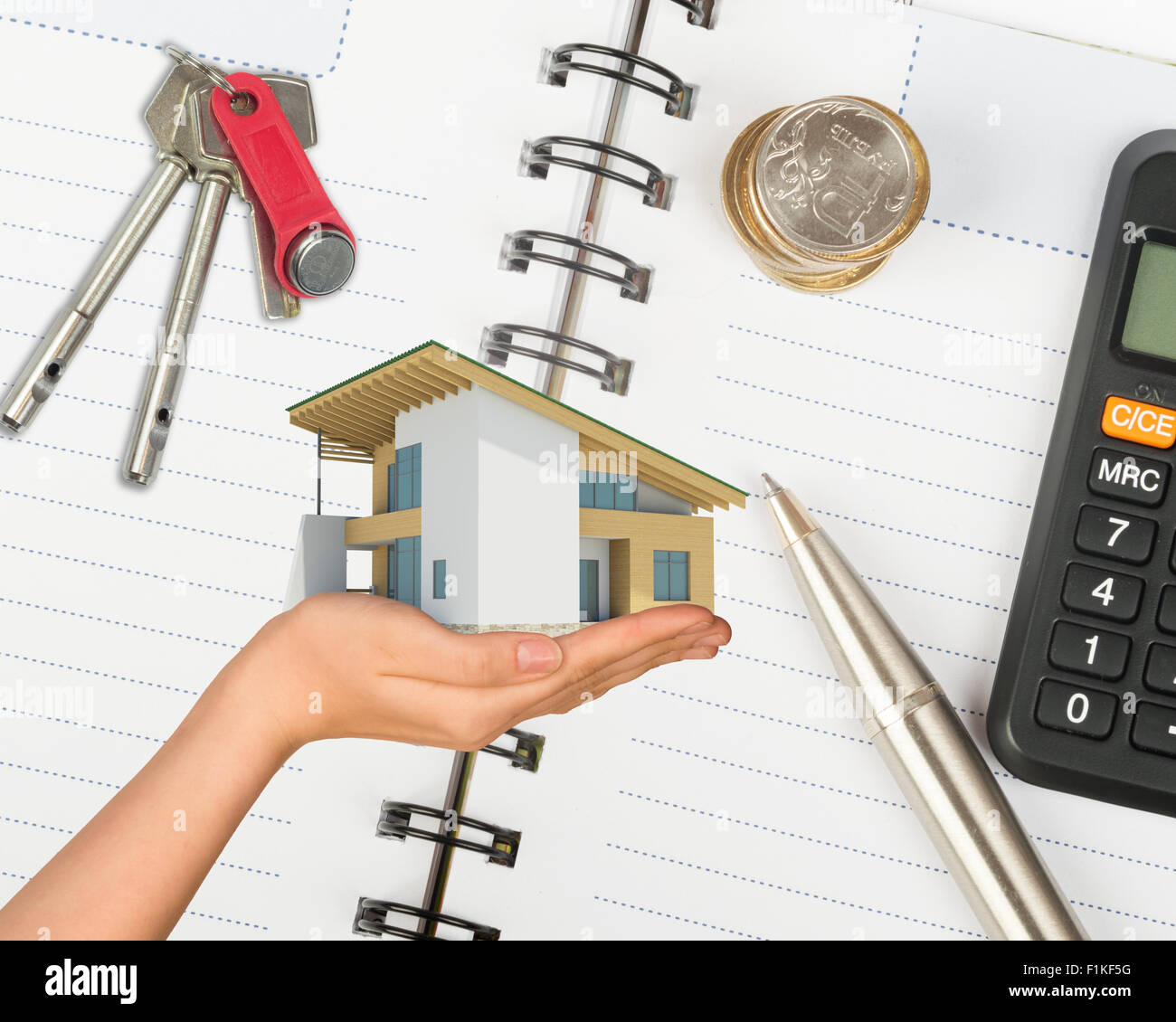 Humans hand holding house with key and coins Stock Photo - Alamy