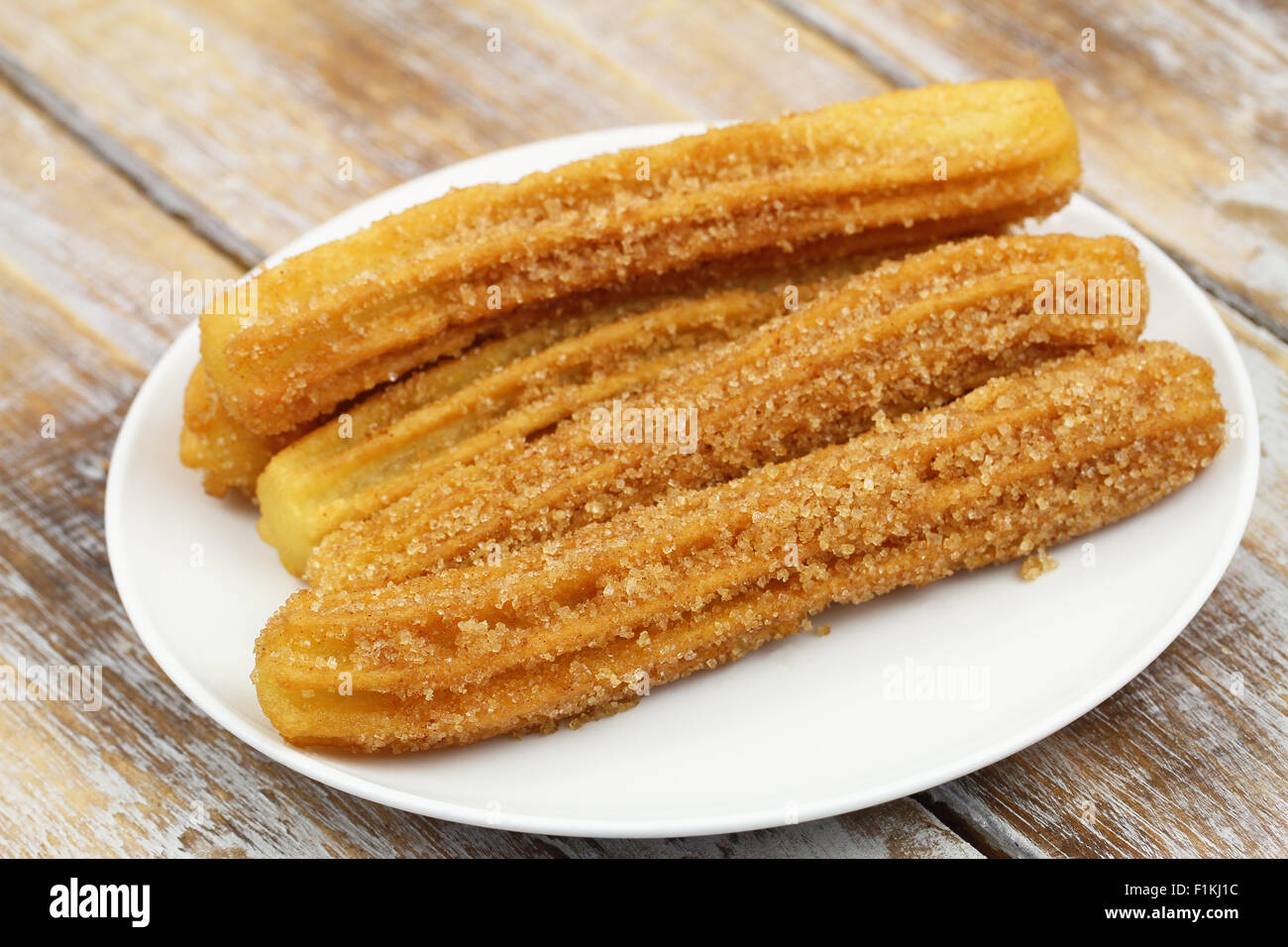 Churros on white plate on rustic wooden surface Stock Photo - Alamy