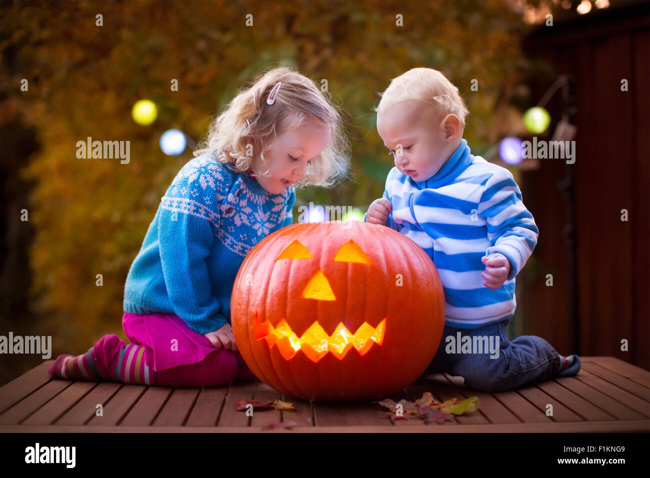 Little girl and boy carving pumpkin at Halloween. Dressed up children ...