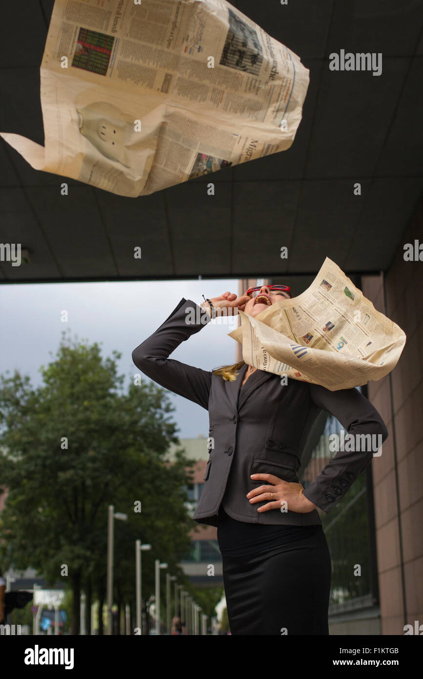 Young blonde business woman with a flying newspaper above her head in ...