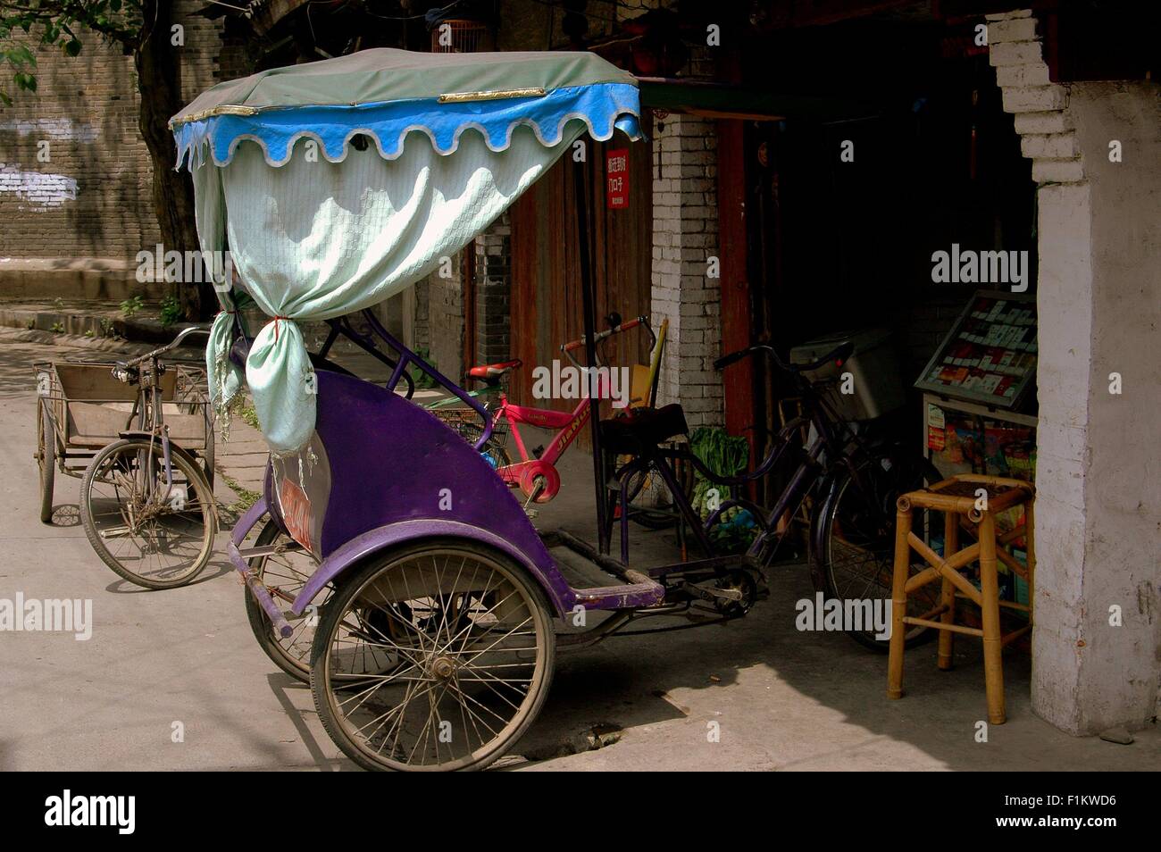 Pengzhou, China: A parked pedicab in front of a small store on Hua Lu ...