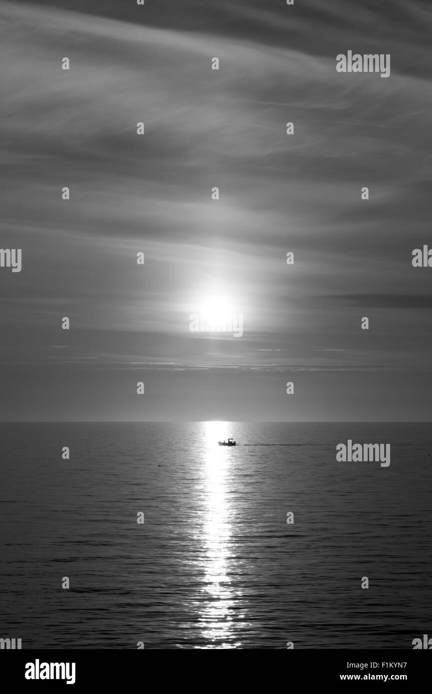 B&W photo of Boat crossing the sun ray thats reflecting on the sea as ...